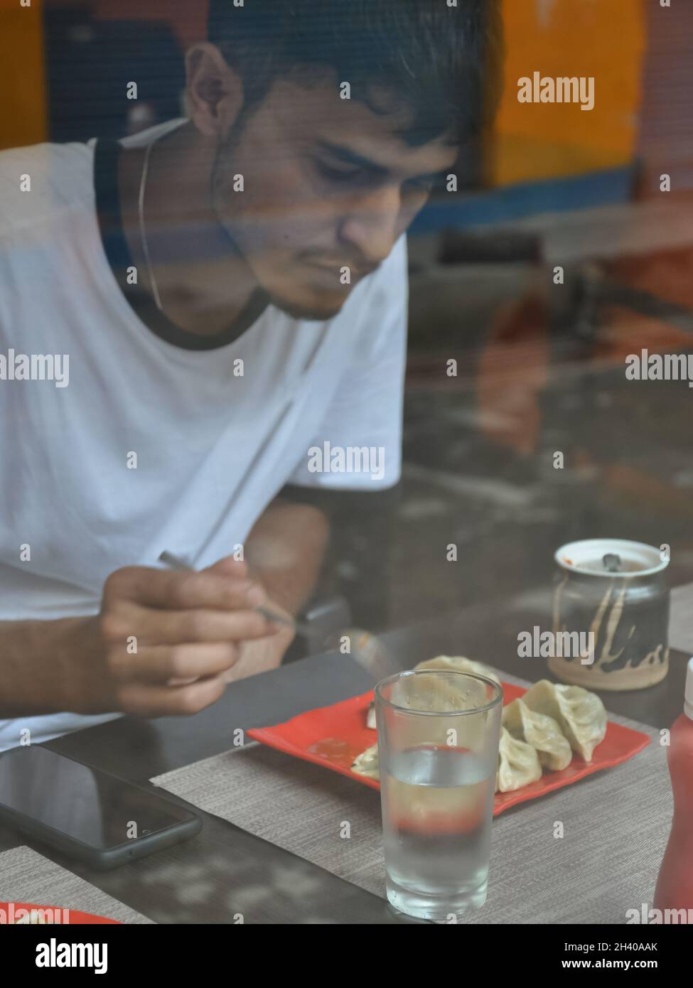 View of a young guy eating fast food in the cafe seen through the ...