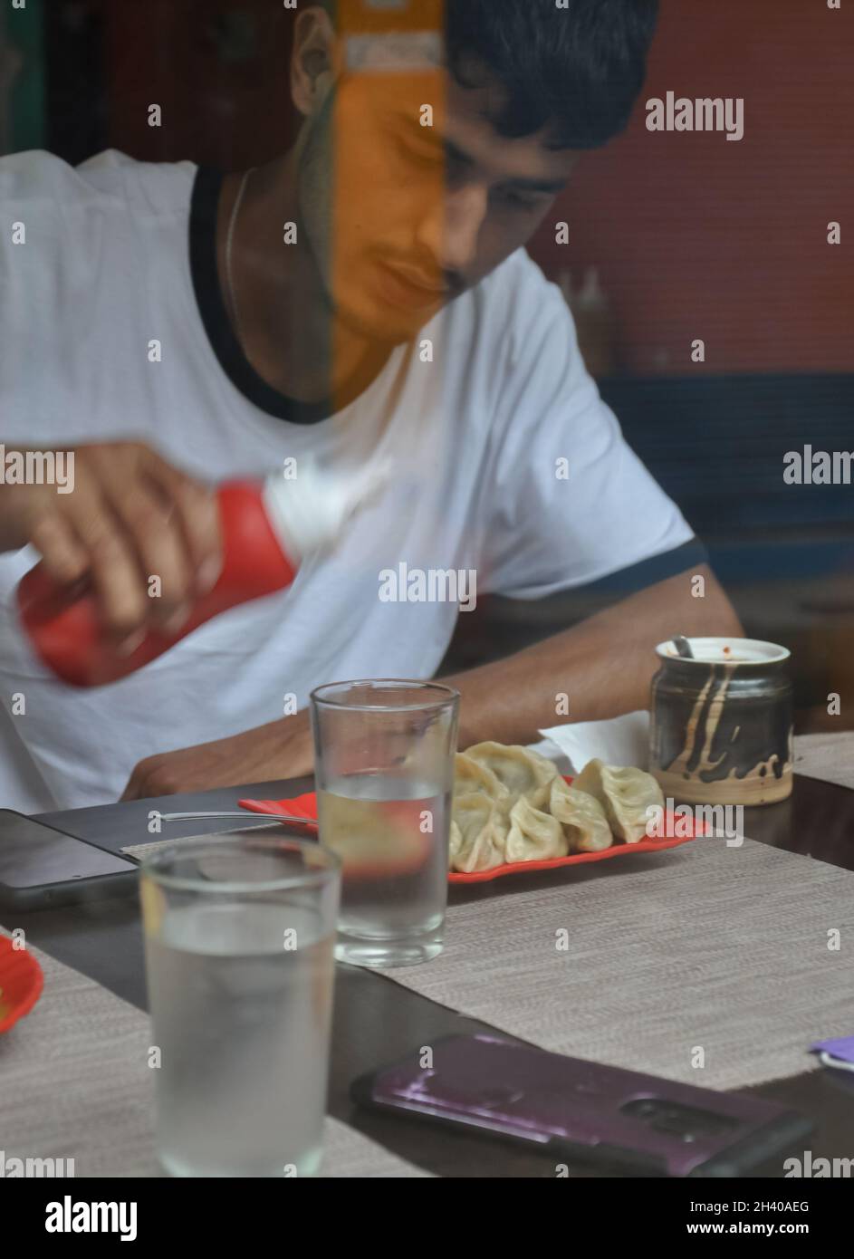View of a young guy eating fast food in the cafe seen through the ...
