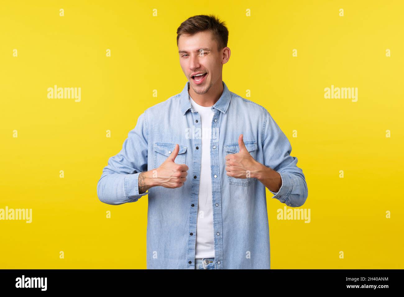 Handsome smiling young man showing thumbs-up and winking. Confident ...