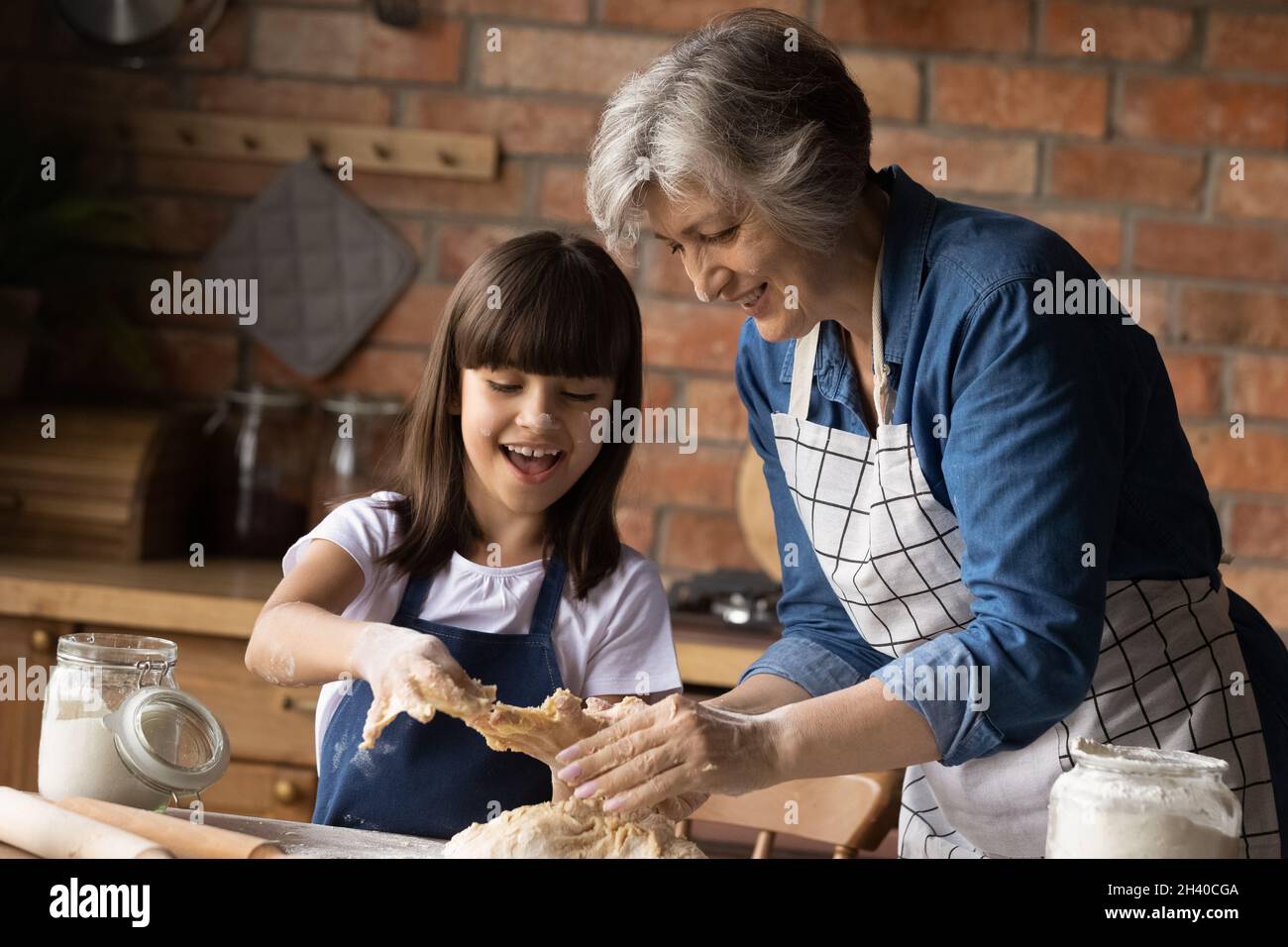 Cheerful granddaughter kid helping happy grandma to knead dough Stock ...