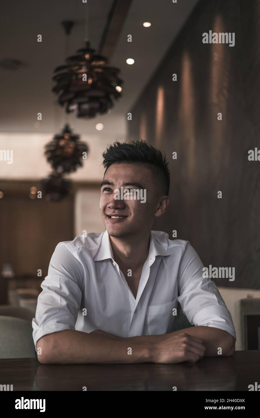 Asian young handsome man sitting in coffee shop and smiling. Chinese ...