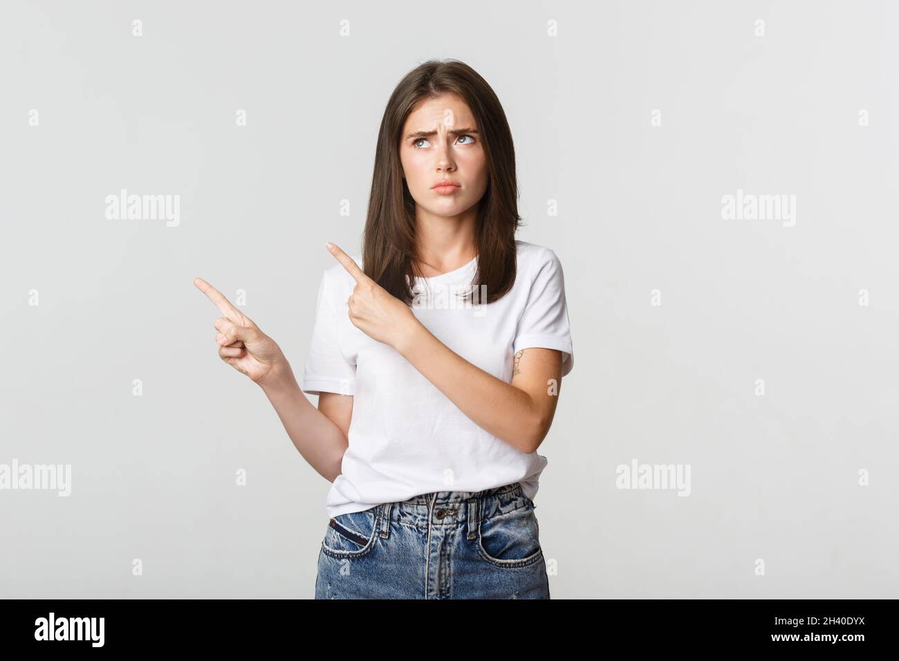 Upset cute girl pointing upper left corner, express regret Stock Photo ...