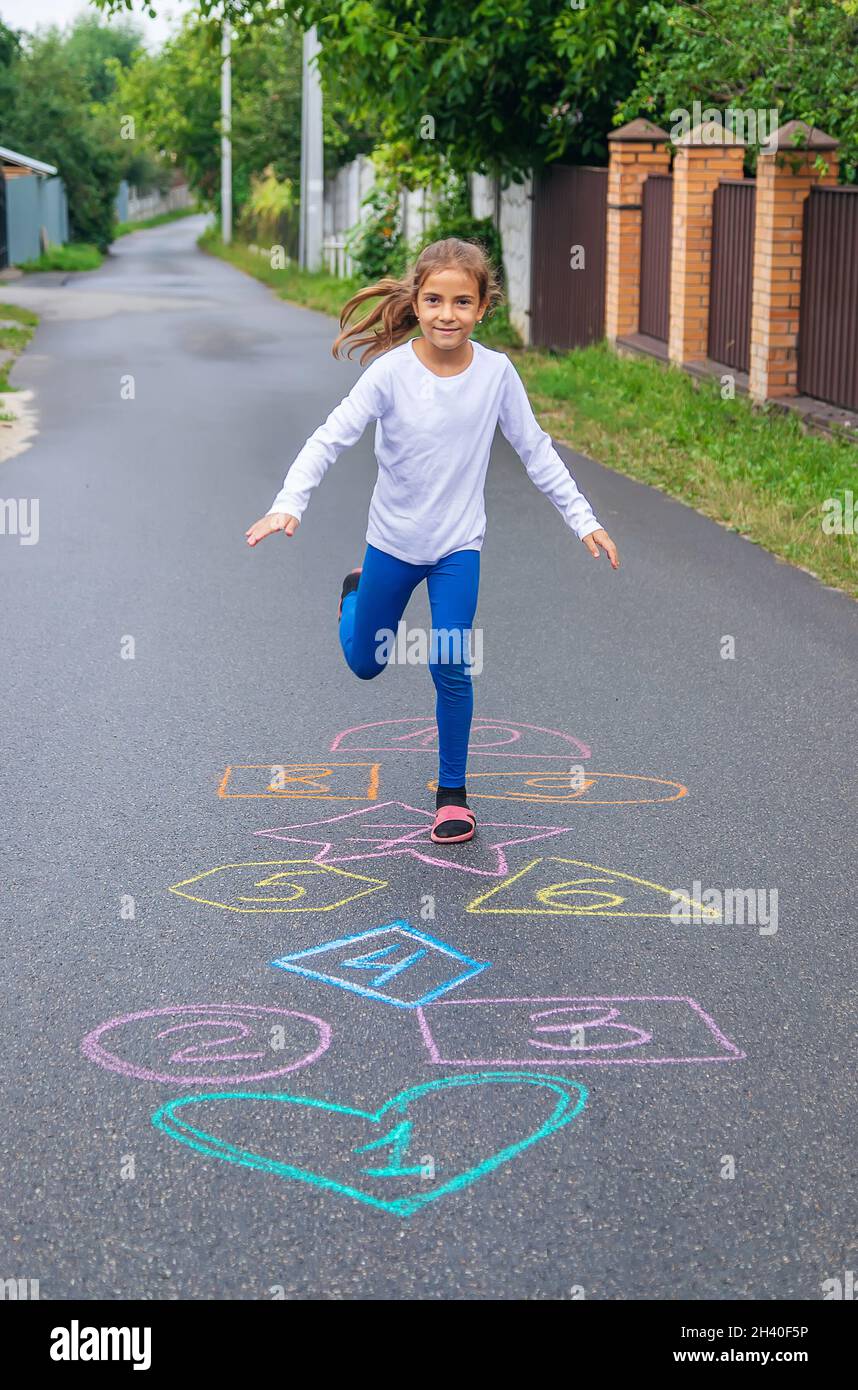 Child jumping classics on the street. Selective focus. Kid Stock Photo ...