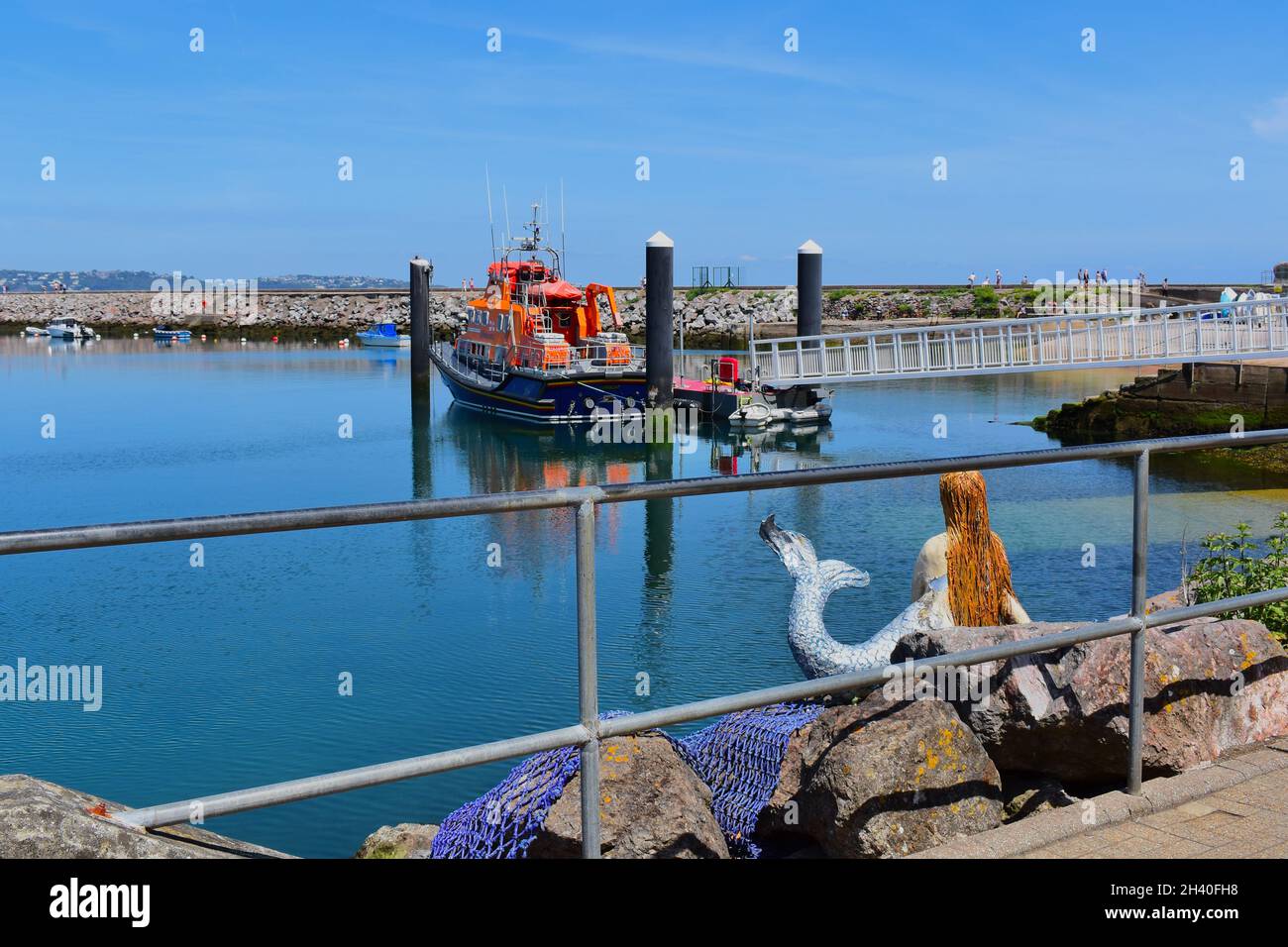 Mermaid sculpture sitting overlooking marina and the Brixham RNLI ...