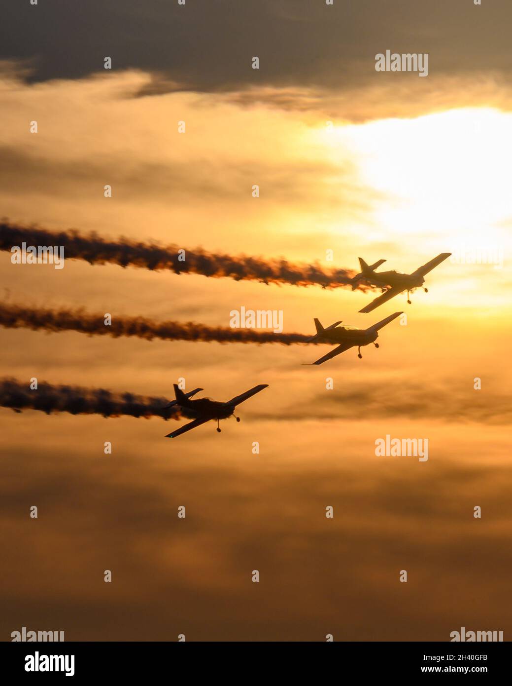 A vertical shot of three planes flying together on a sunset sky ...
