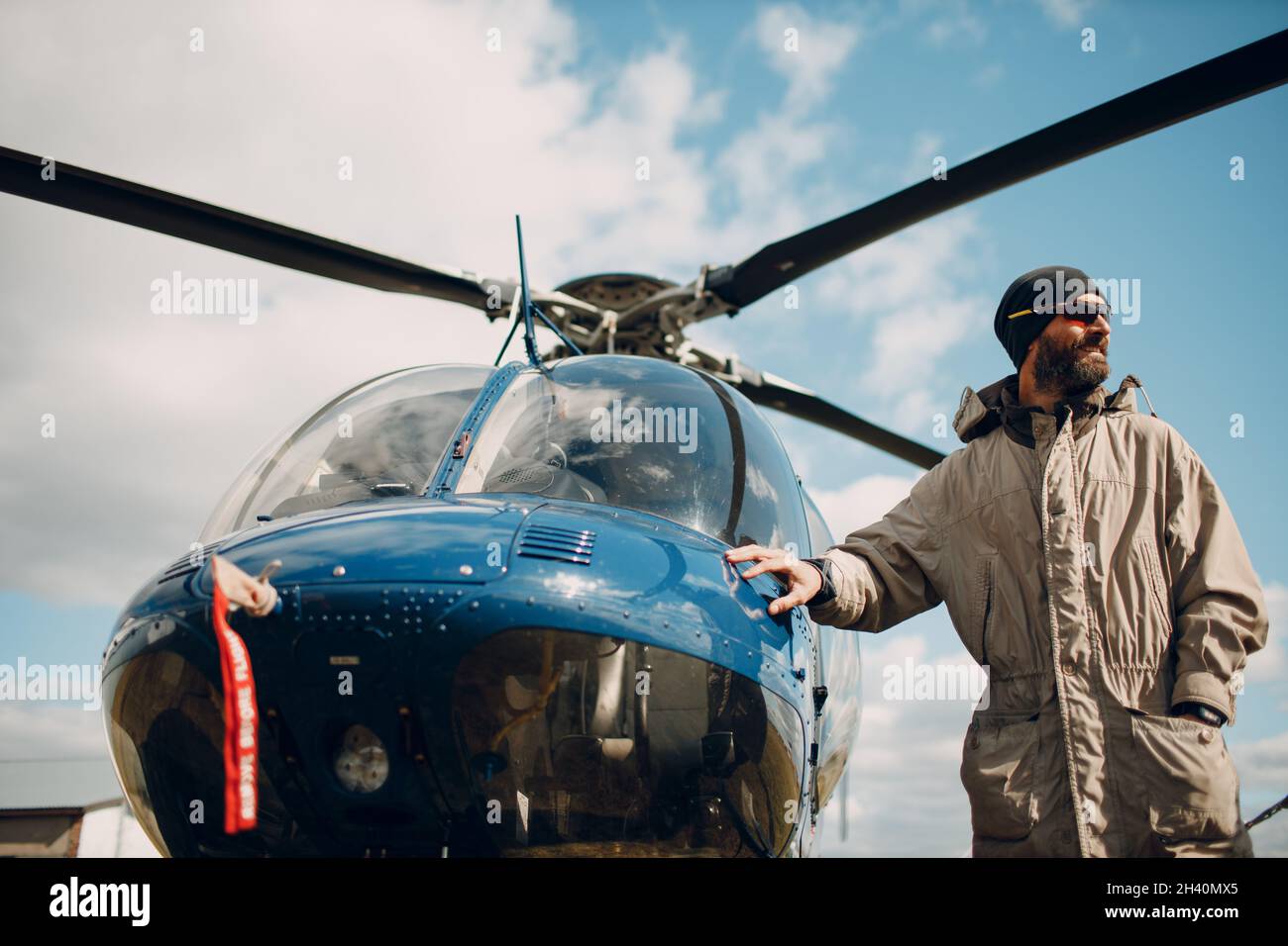 Portrait of helicopter pilot standing near vehicle in field airport ...
