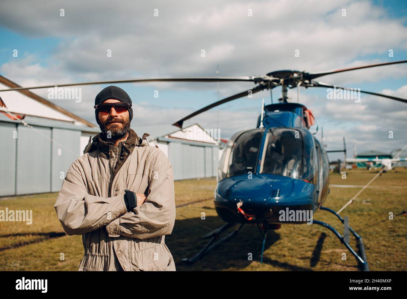 Portrait of helicopter pilot standing near vehicle in field airport ...