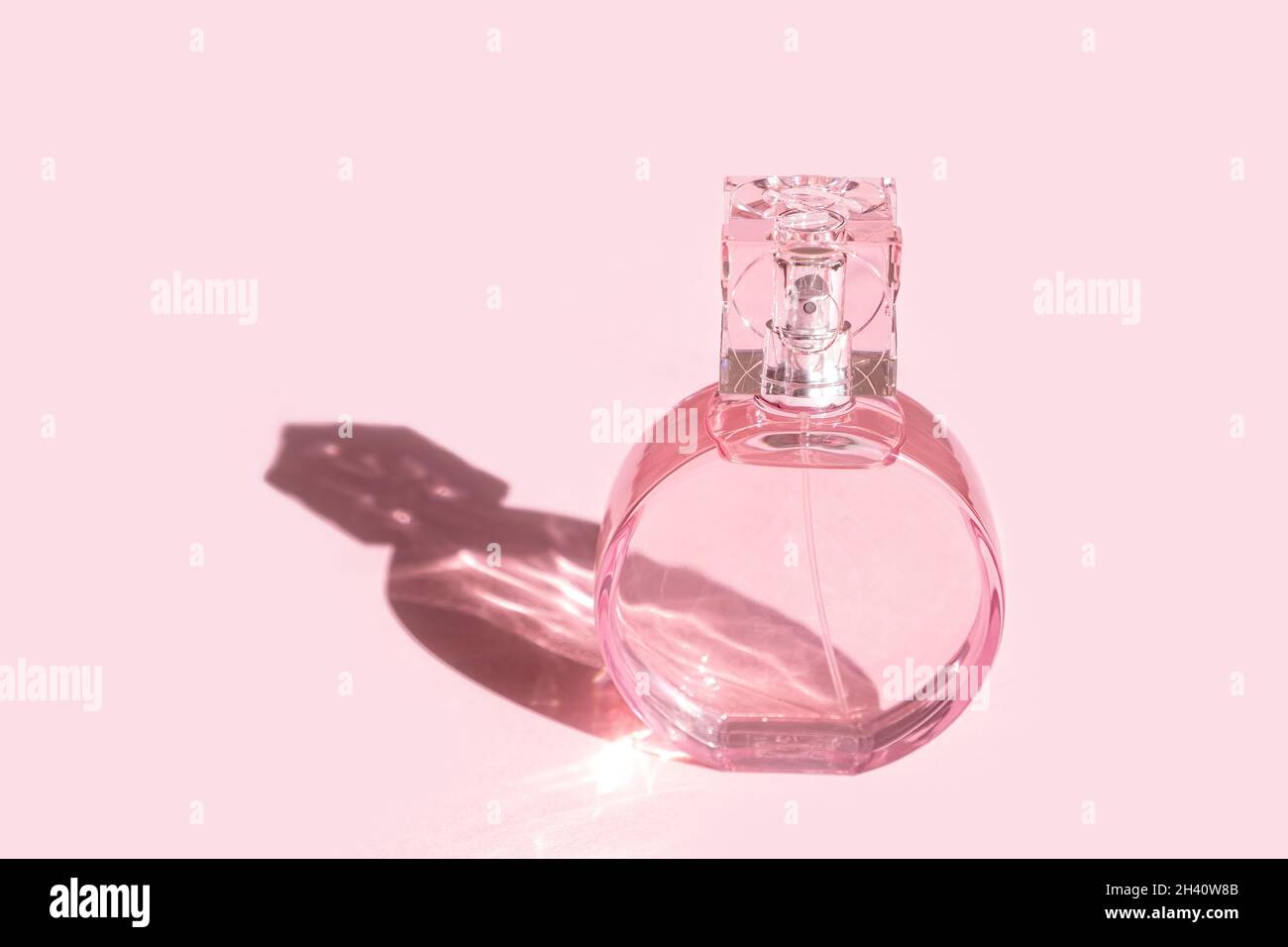 Transparent pink perfume bottle on pink background with strong shadow ...