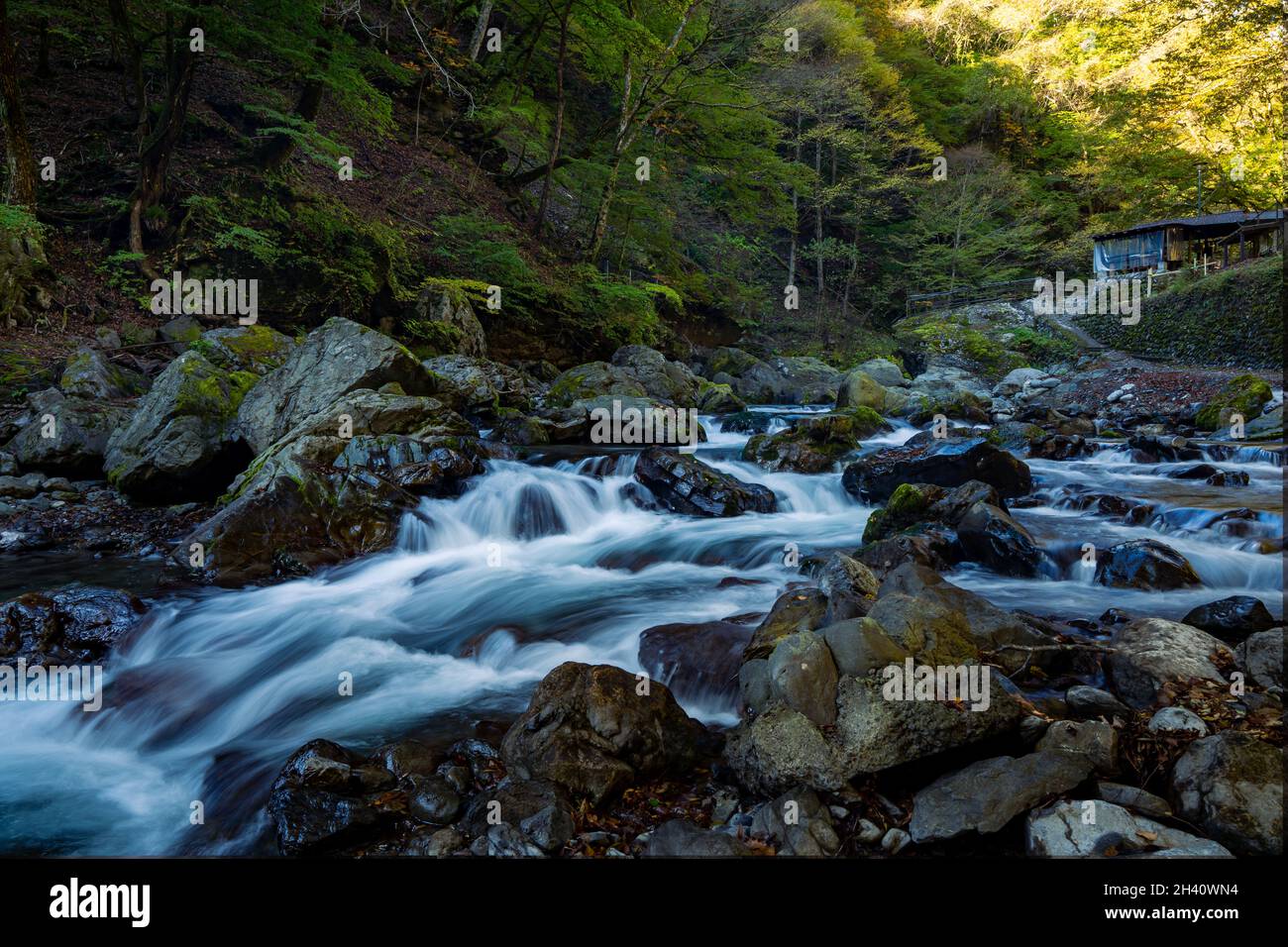 Slow shutter image of the cascading Tama river flowing over boulders in ...