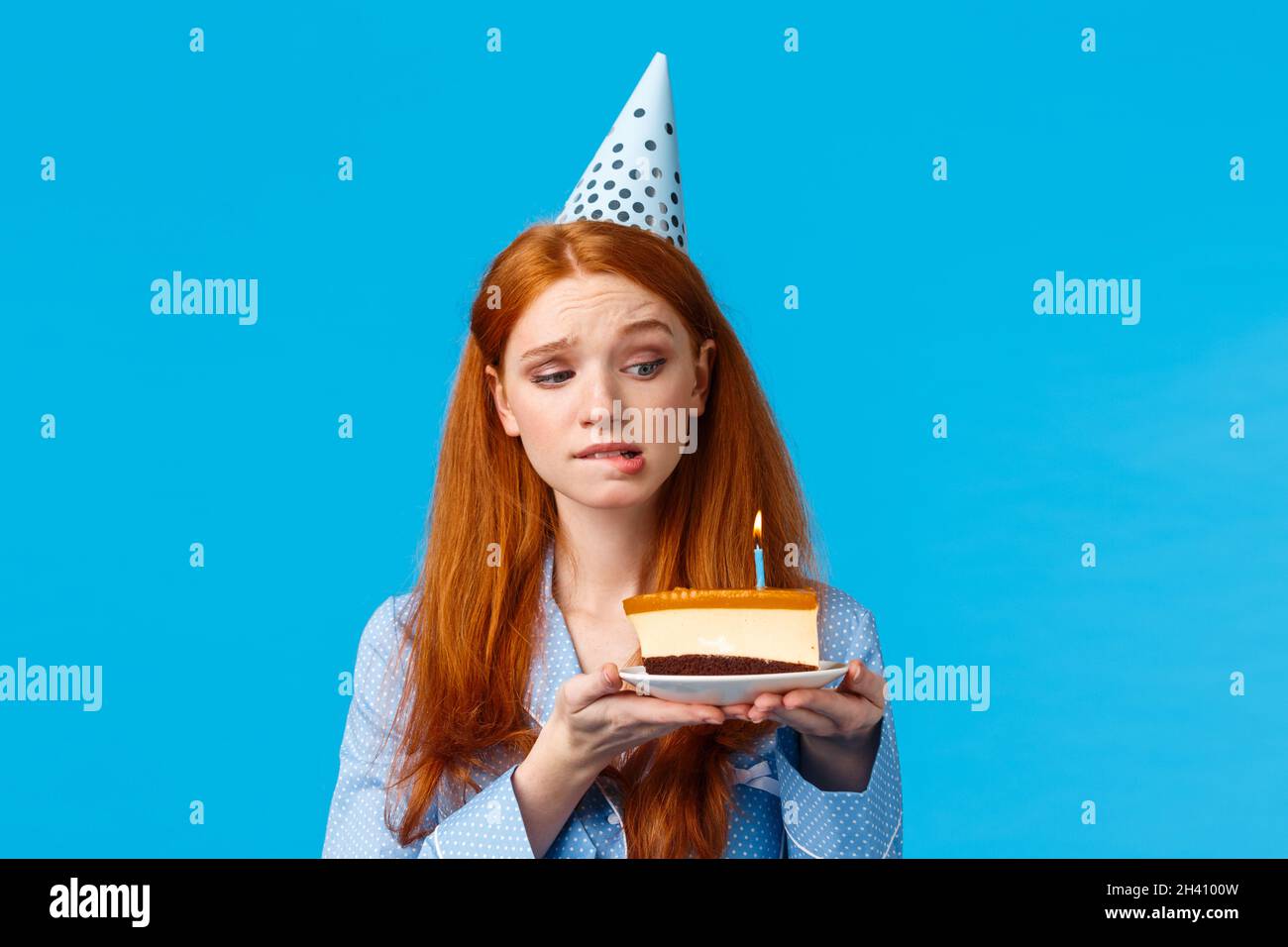 Attractive caucasian redhead woman in birthday cap, holding delicious ...