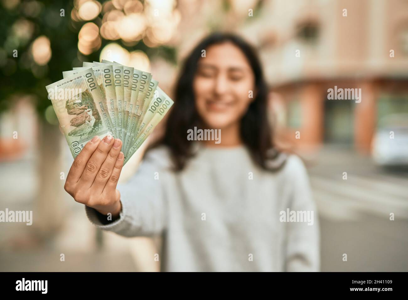 Young middle east girl smiling happy holding chile pesos banknotes at ...