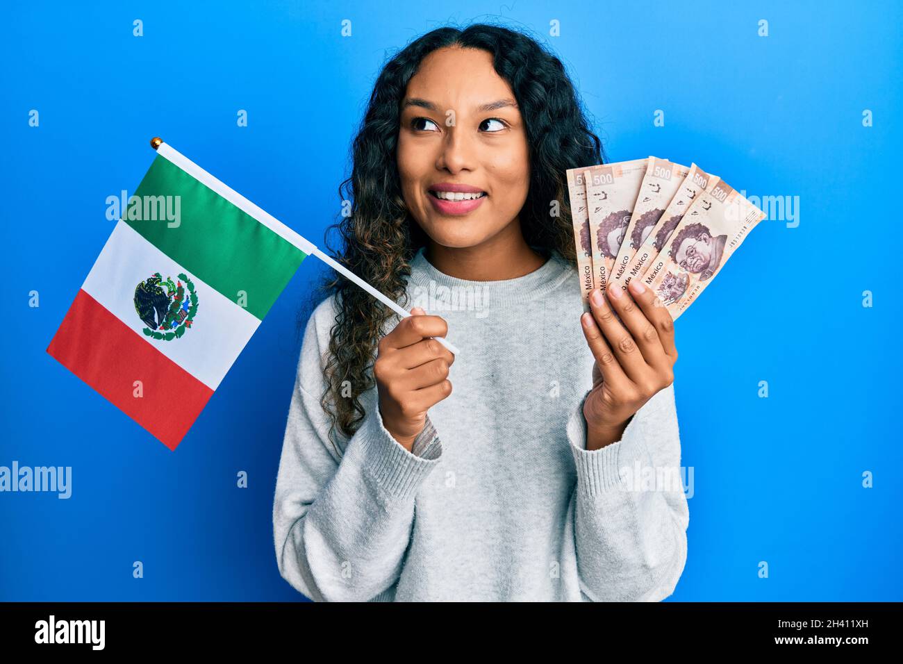 Young latin woman holding mexico flag and mexican pesos banknotes ...