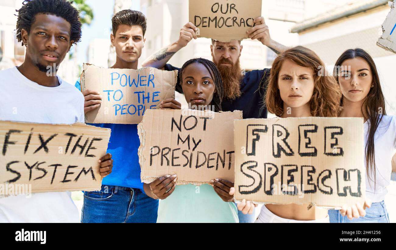 Group of young hispanic activists holding protest banner protesting at ...