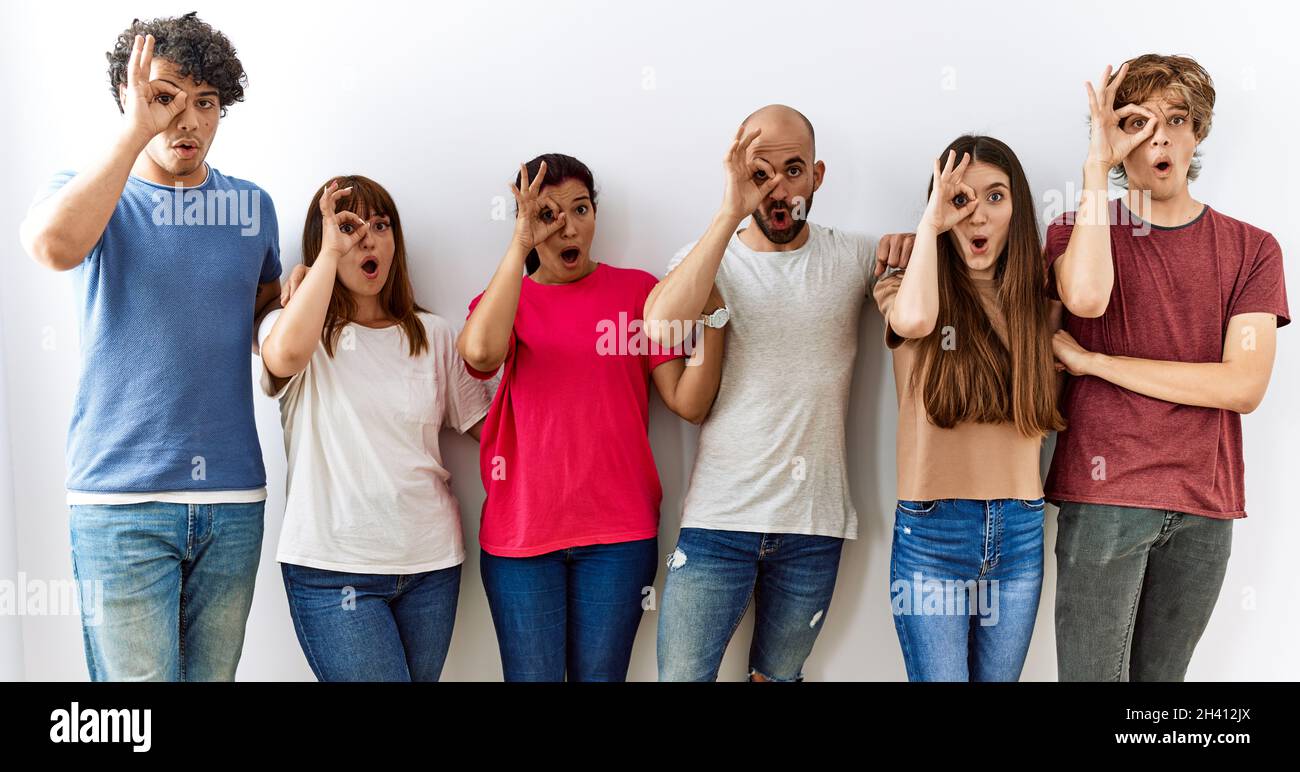 Group of young friends standing together over isolated background doing ...