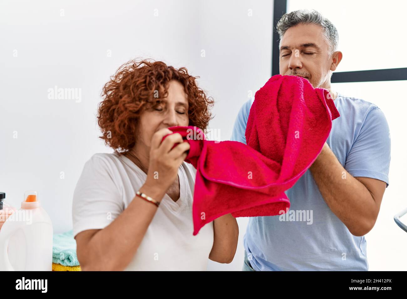 Middle age man and woman couple smiling confident smelling clothes at laundry Stock Photo - Alamy