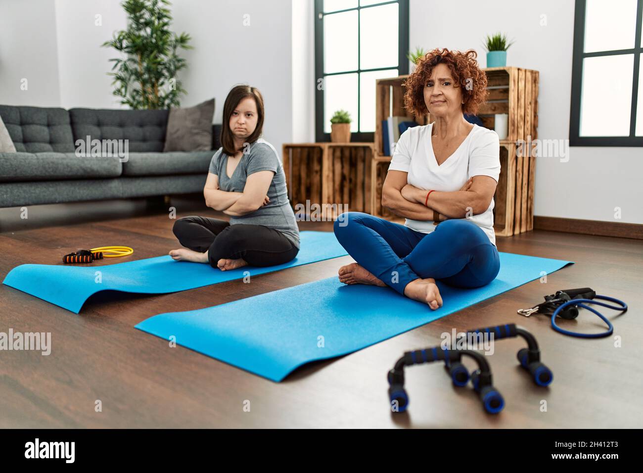 Family of mother and down syndrome daughter doing exercise at home ...