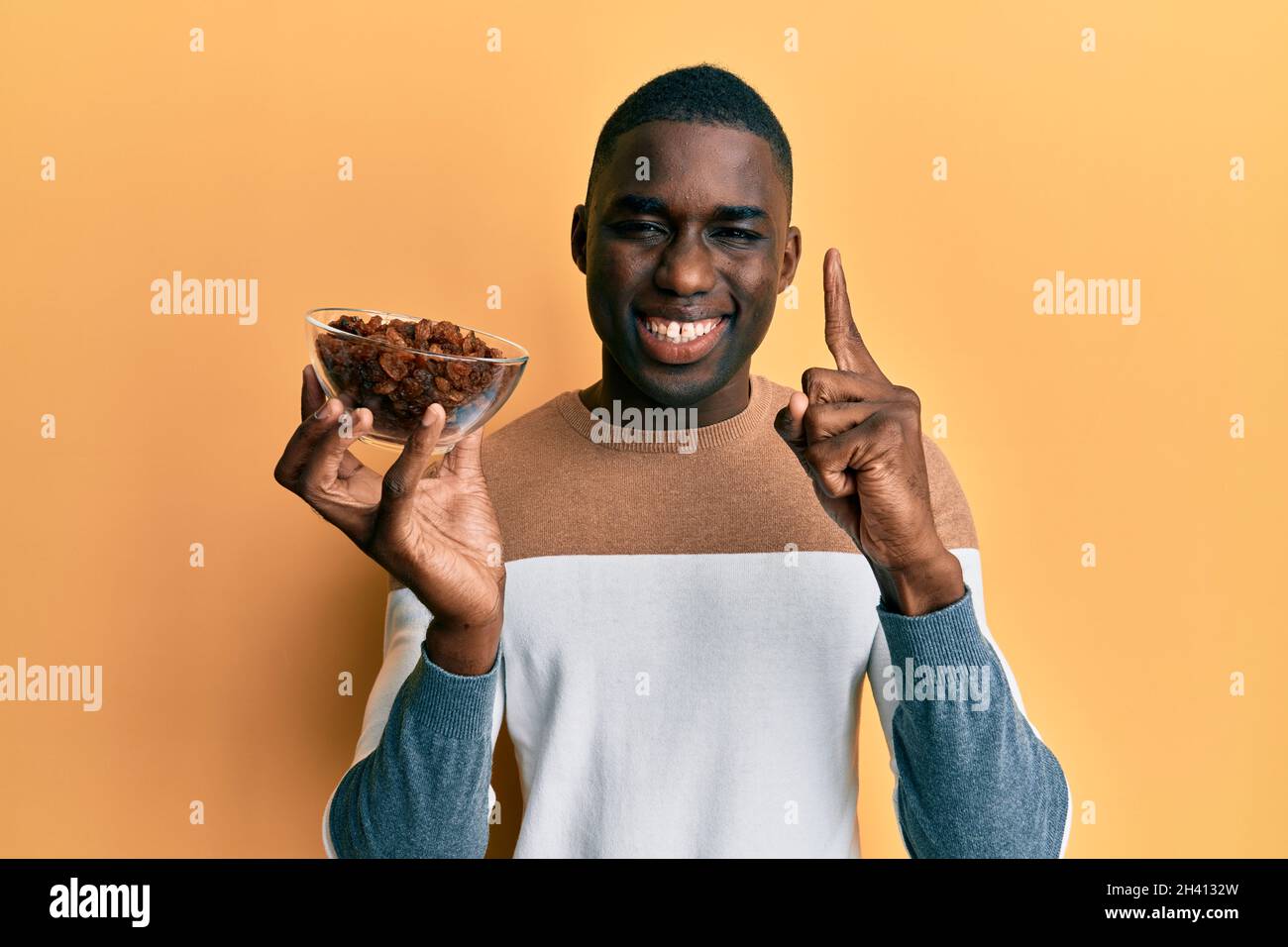 Young african american man holding bowl with raisins smiling with an ...