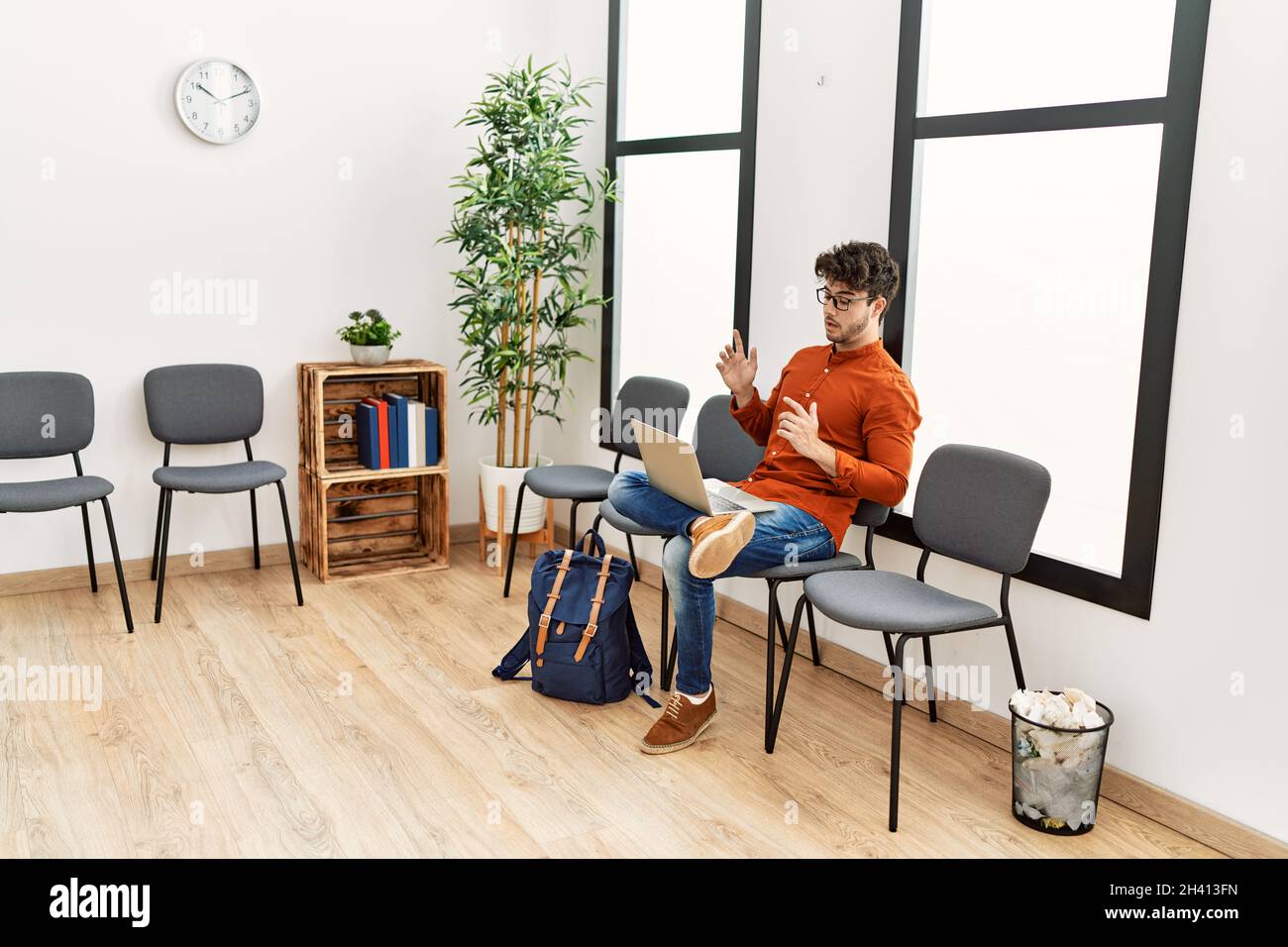 Young hispanic man smiling confident having video call at waiting room ...