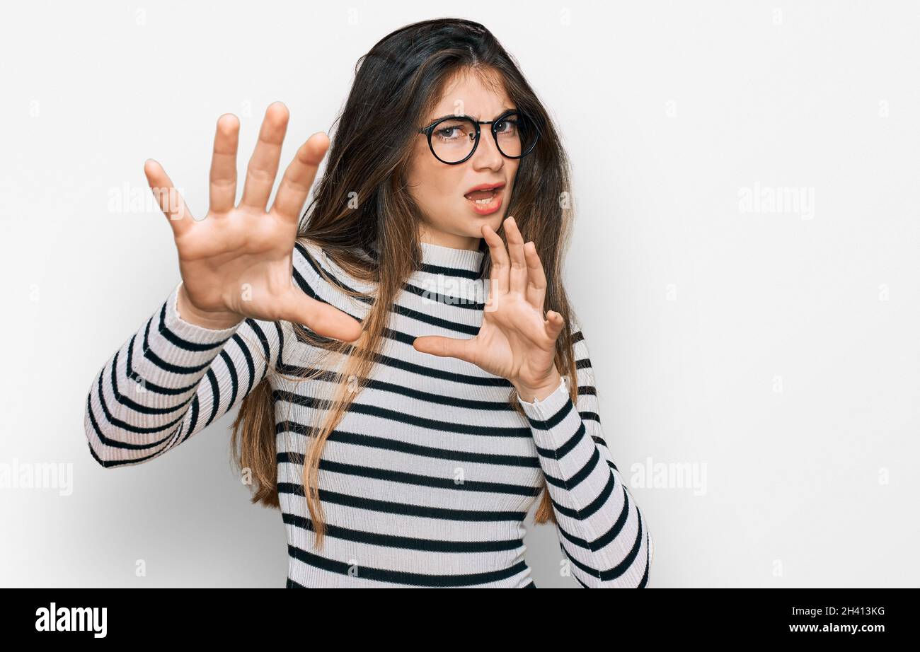 Young beautiful teen girl wearing casual clothes and glasses afraid and ...