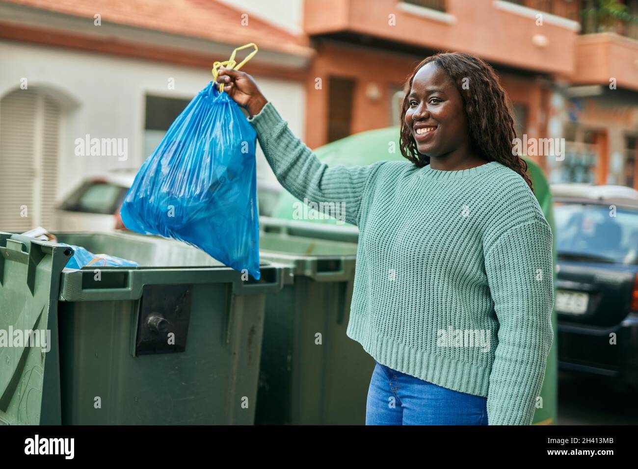 Young african woman throwing out the trash at the city Stock Photo - Alamy