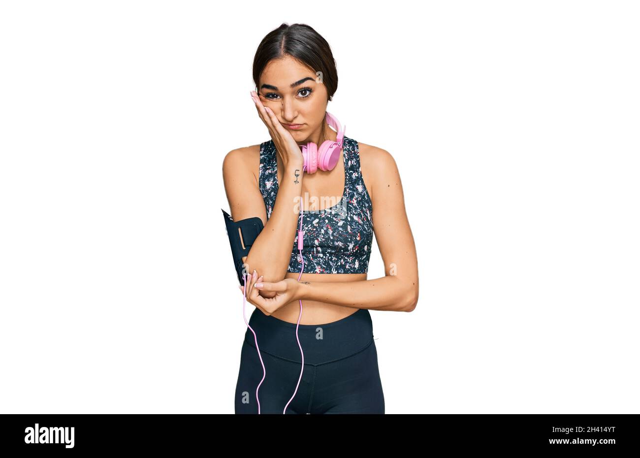 Beautiful brunette woman wearing gym clothes and using headphones ...