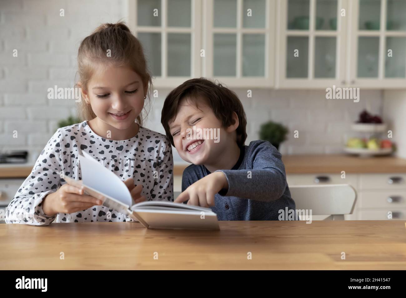 Happy little children reading funny story in paper book Stock Photo - Alamy