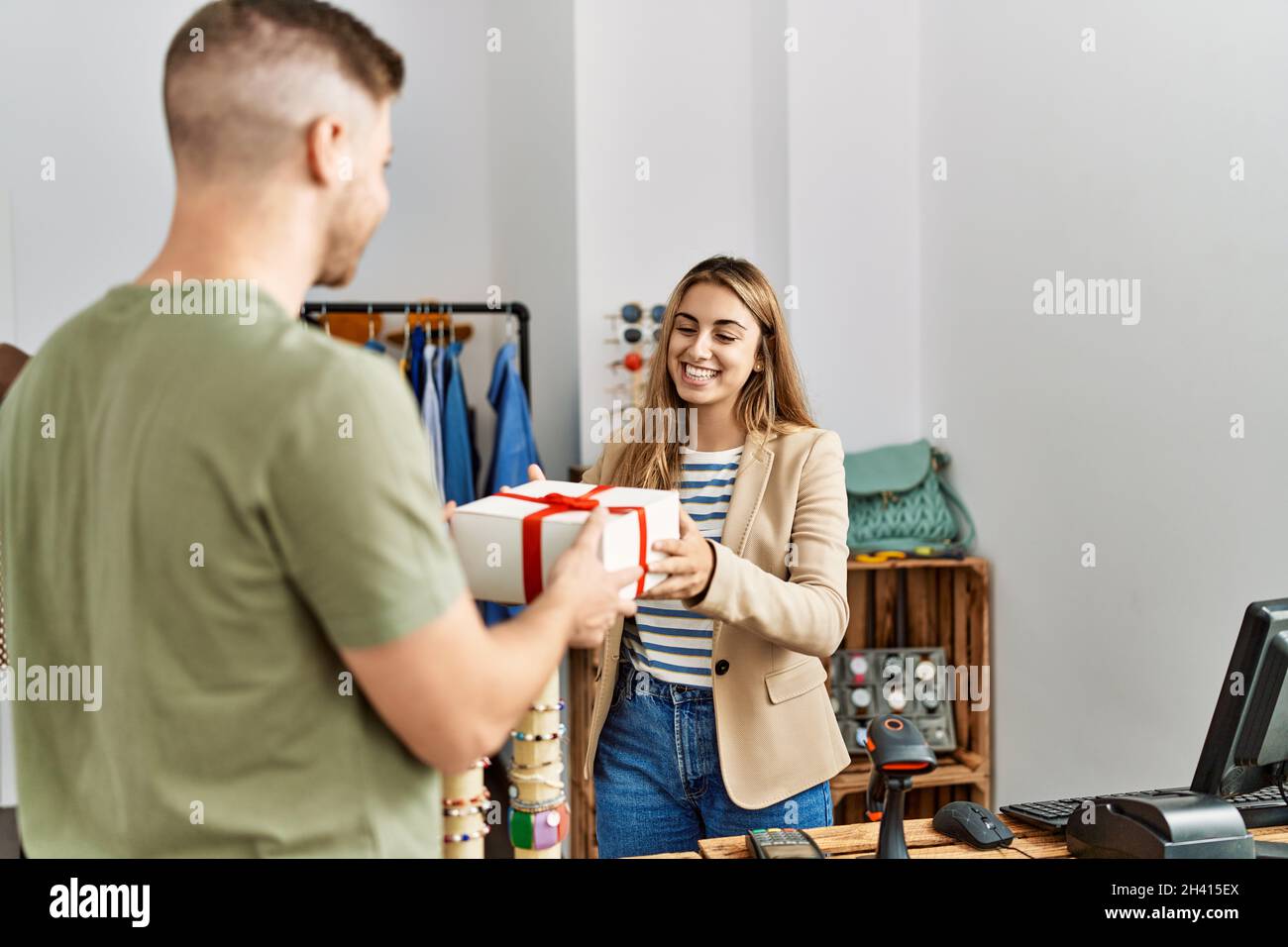 Young shopkeeper giving gift to customer at clothing store Stock Photo ...