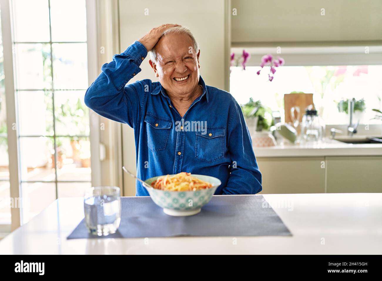 Senior man with grey hair eating pasta spaghetti at home confuse and ...