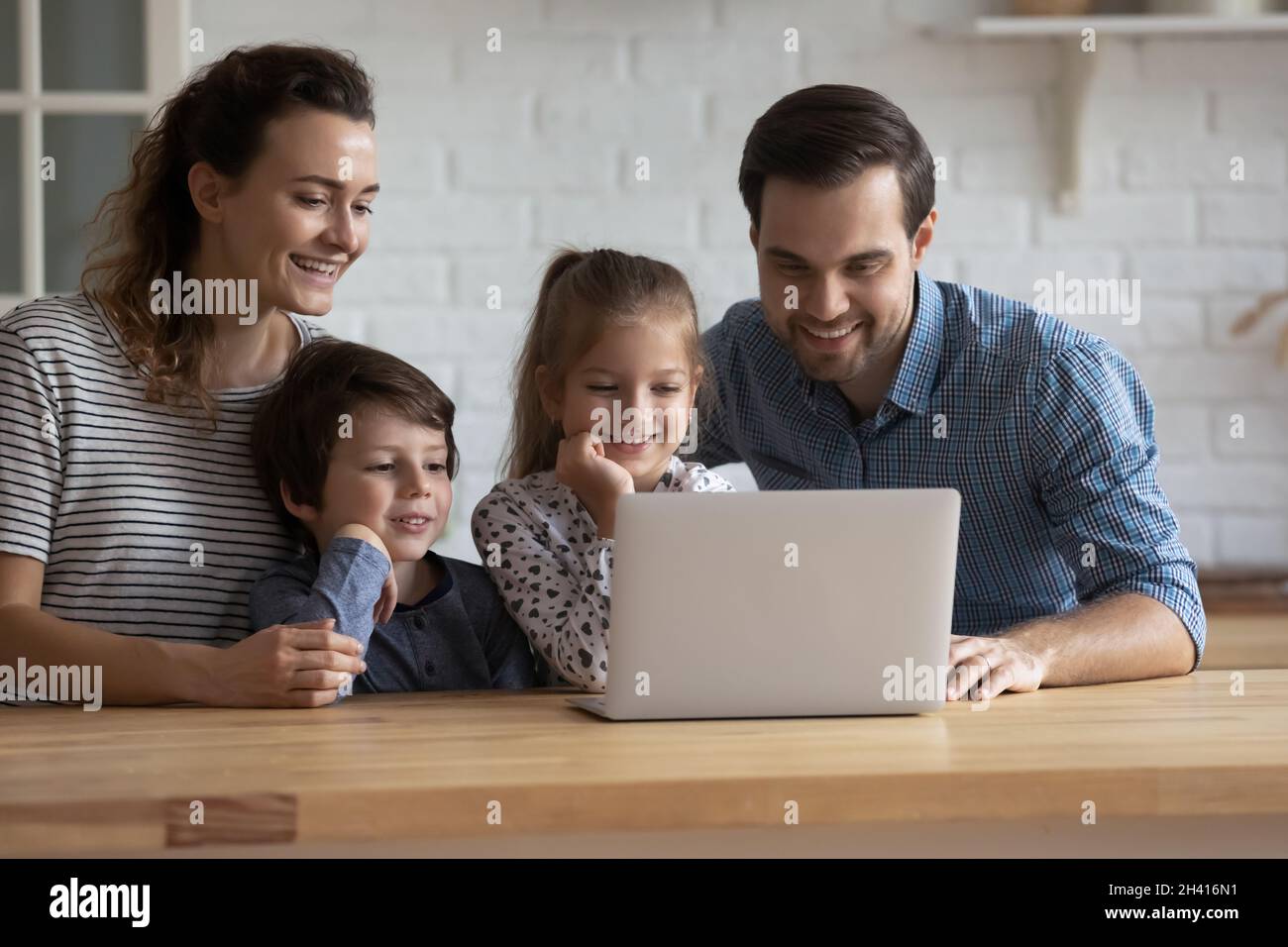 Happy caring young parents using computer with small kids Stock Photo ...