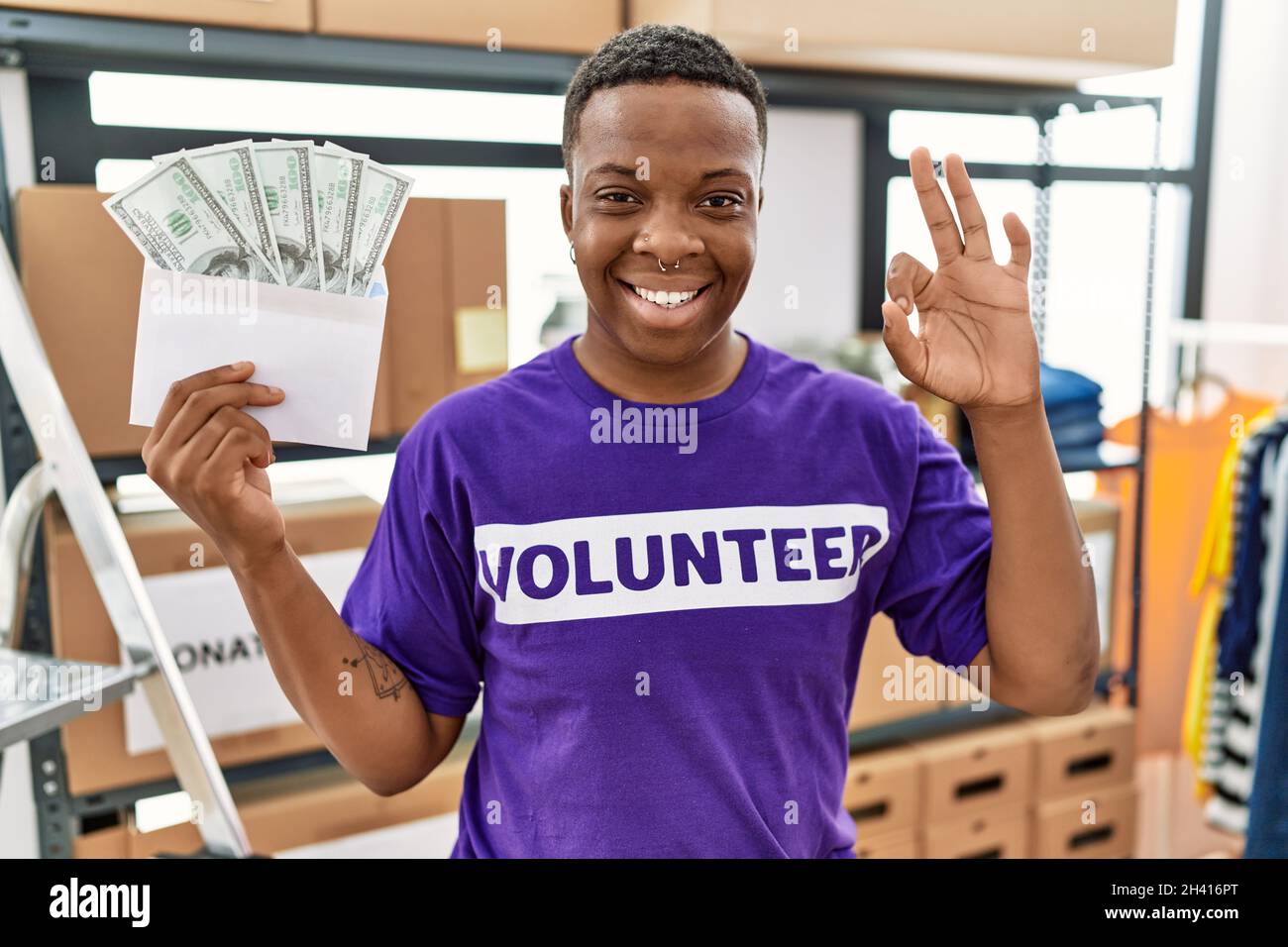 Young african volunteer man holding dollars banknotes doing ok sign ...