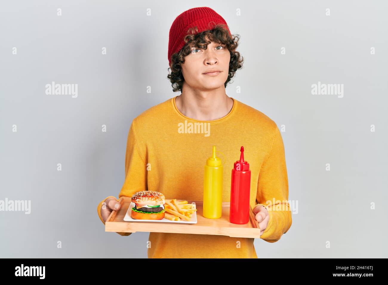 Handsome young man eating a tasty classic burger with ketchup and ...