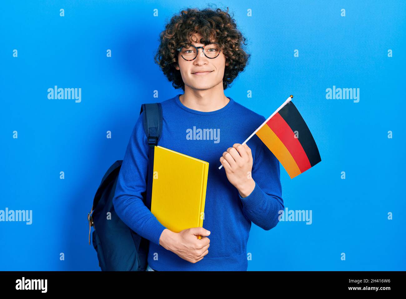 Handsome young man exchange student holding germany flag smiling with a ...