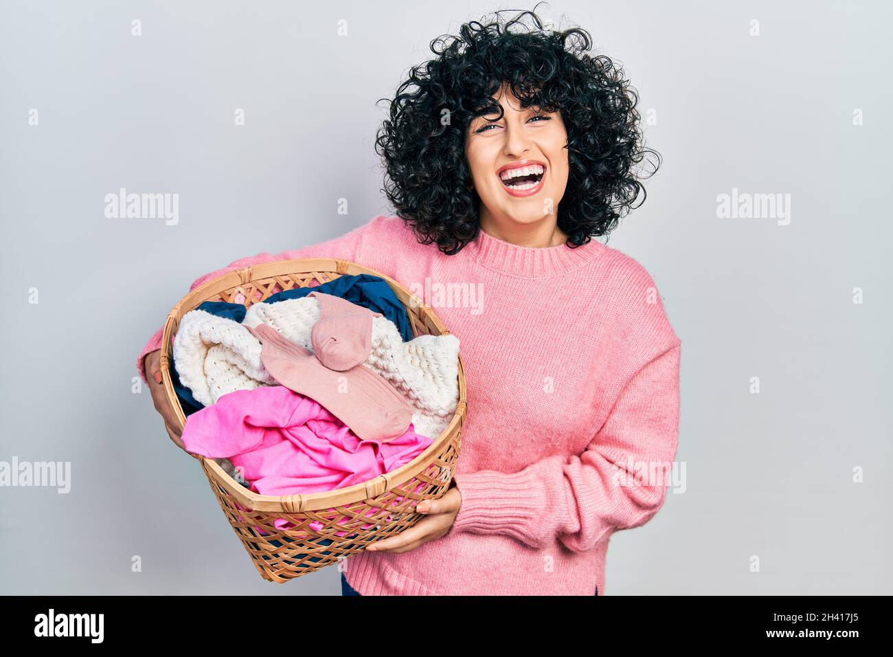 Young middle east woman holding laundry basket smiling and laughing ...
