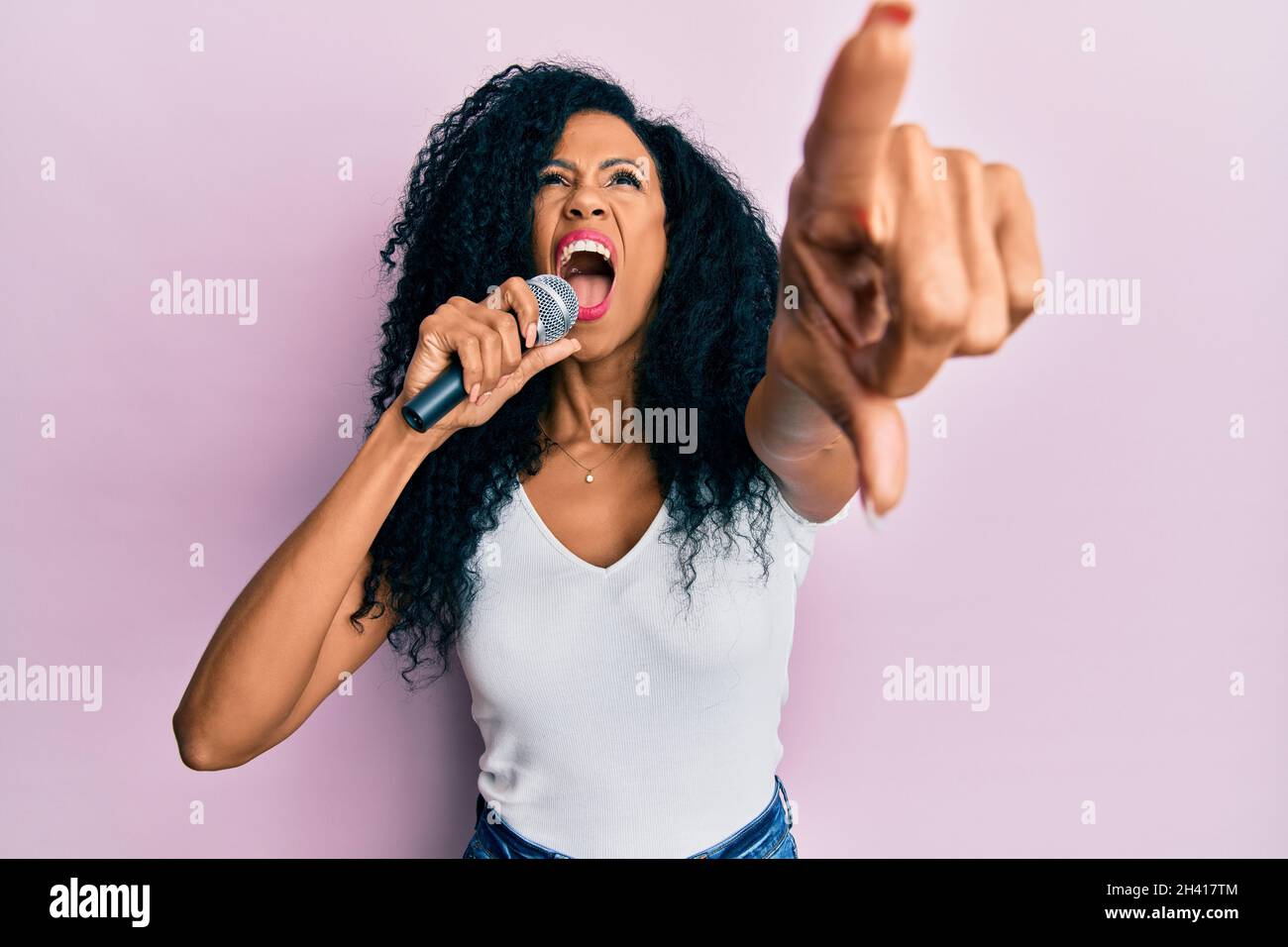 Middle age african american woman singing song using microphone ...