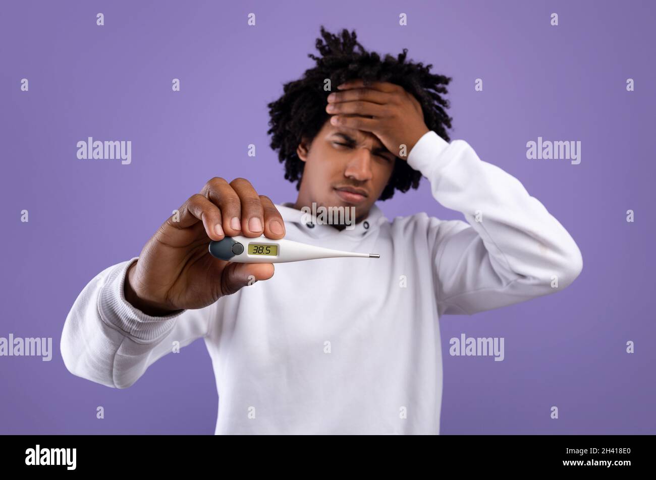Sick black teenager showing thermometer with high temperature numbers ...