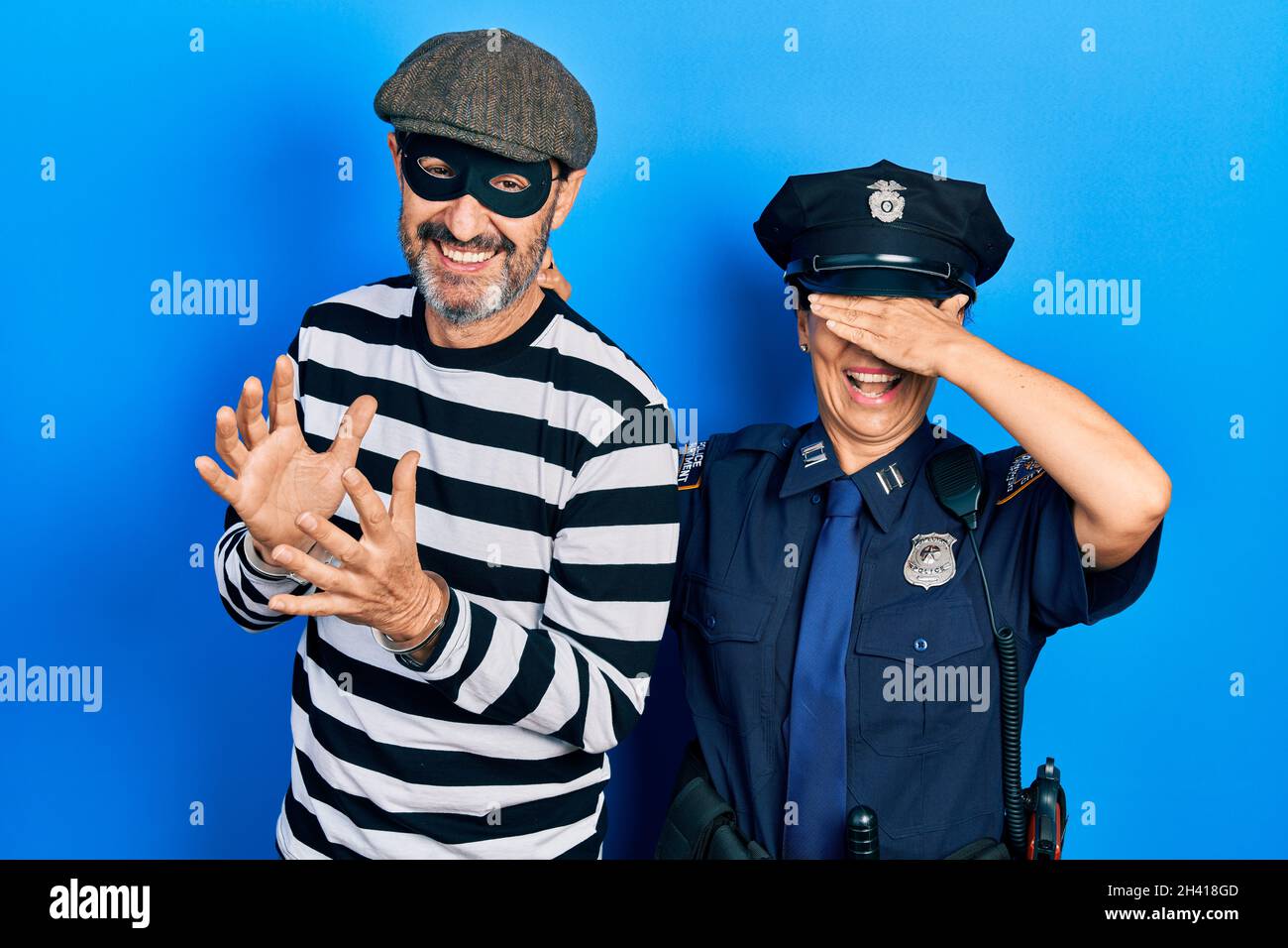 Middle age couple of hispanic woman and man wearing thief and police ...