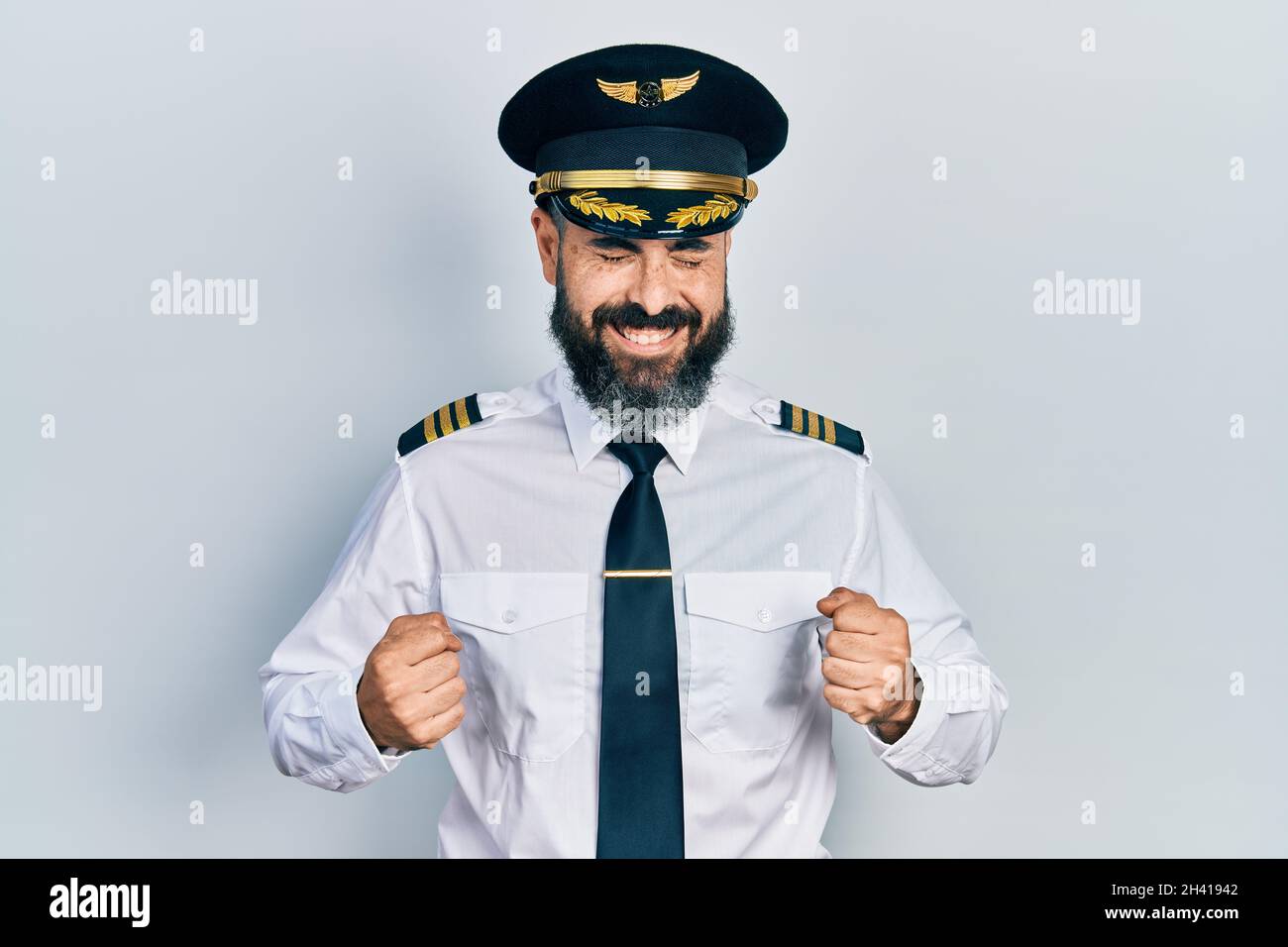 Young hispanic man wearing airplane pilot uniform excited for success ...