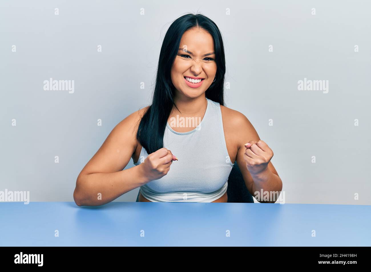 Beautiful hispanic woman with nose piercing sitting on the table ...