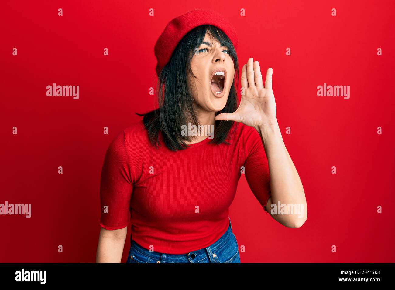 Young hispanic woman wearing french look with beret shouting and ...