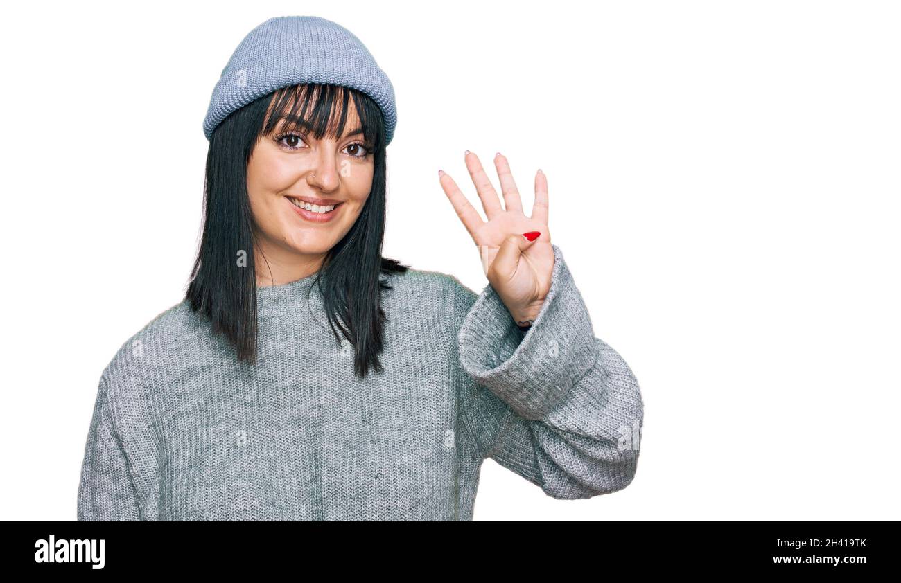 Young hispanic woman wearing cute wool cap showing and pointing up with ...