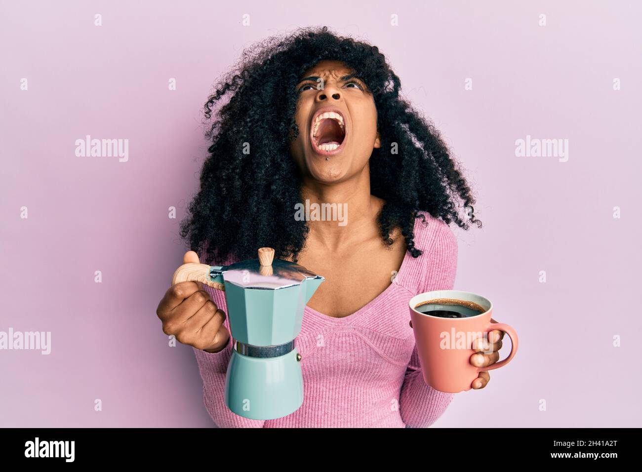 African american woman with afro hair drinking italian coffee angry and ...