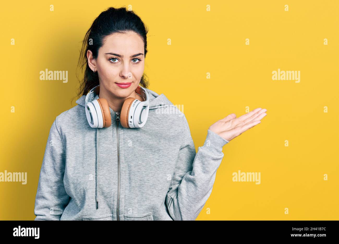 Young hispanic woman wearing gym clothes, using headphones and smart ...