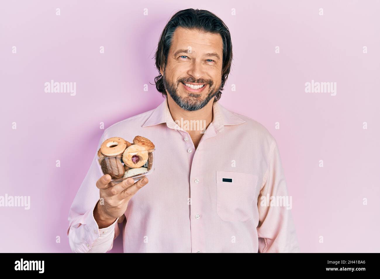 Middle age caucasian man holding sweet pastries looking positive and ...