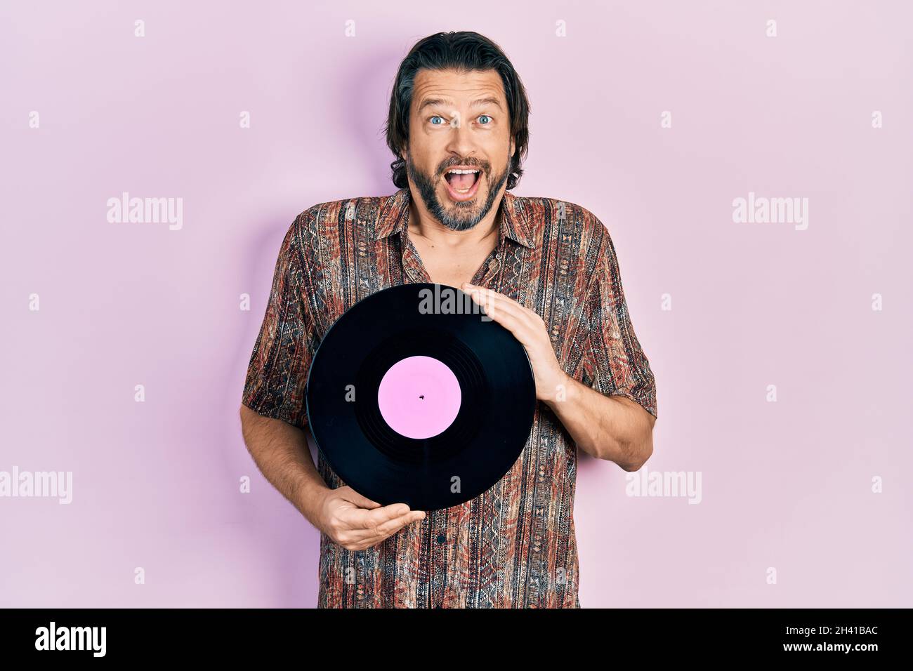 Middle age caucasian man holding vinyl disc celebrating crazy and ...