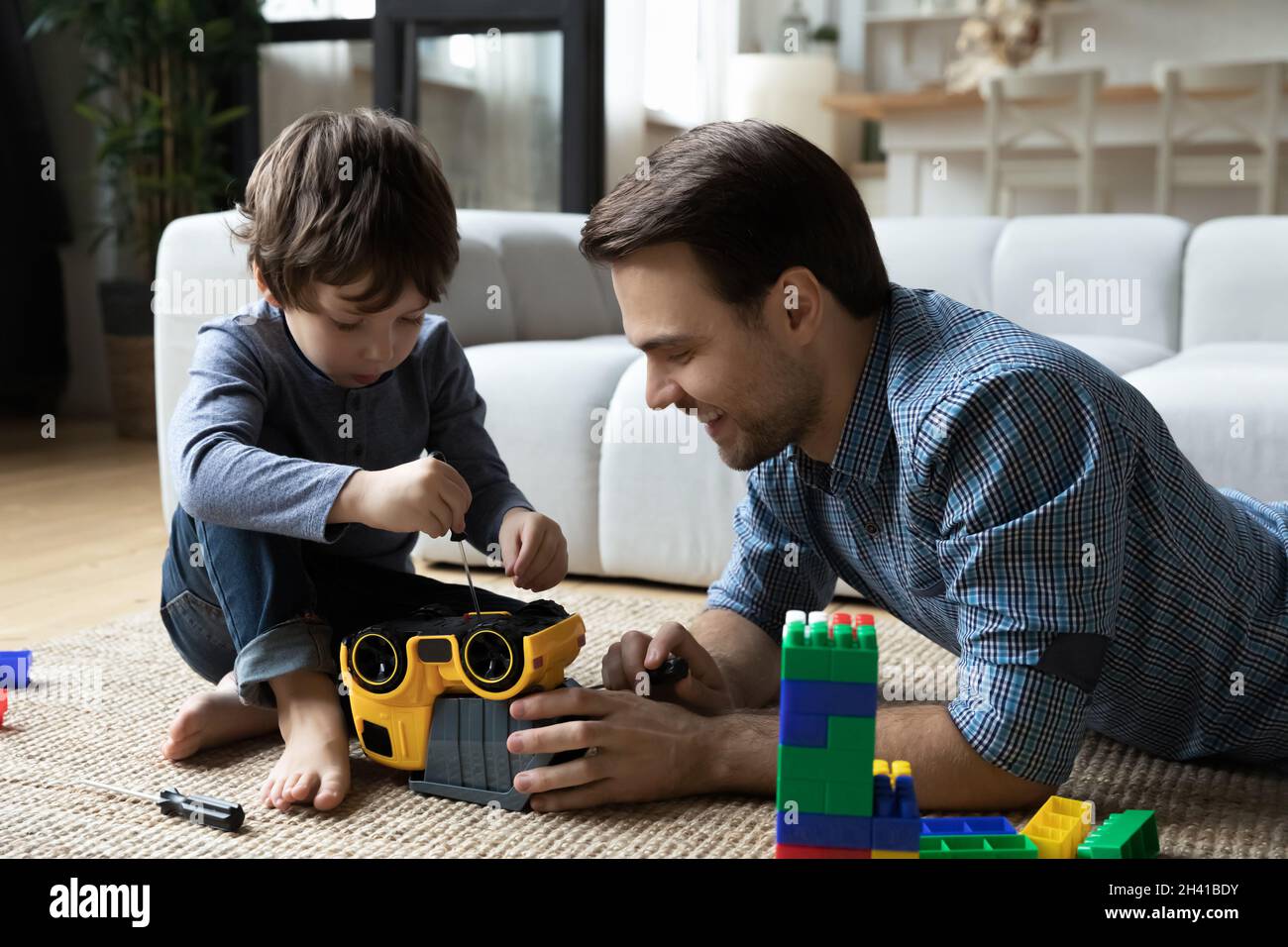 Concentrated small boy fixing car with caring dad Stock Photo - Alamy