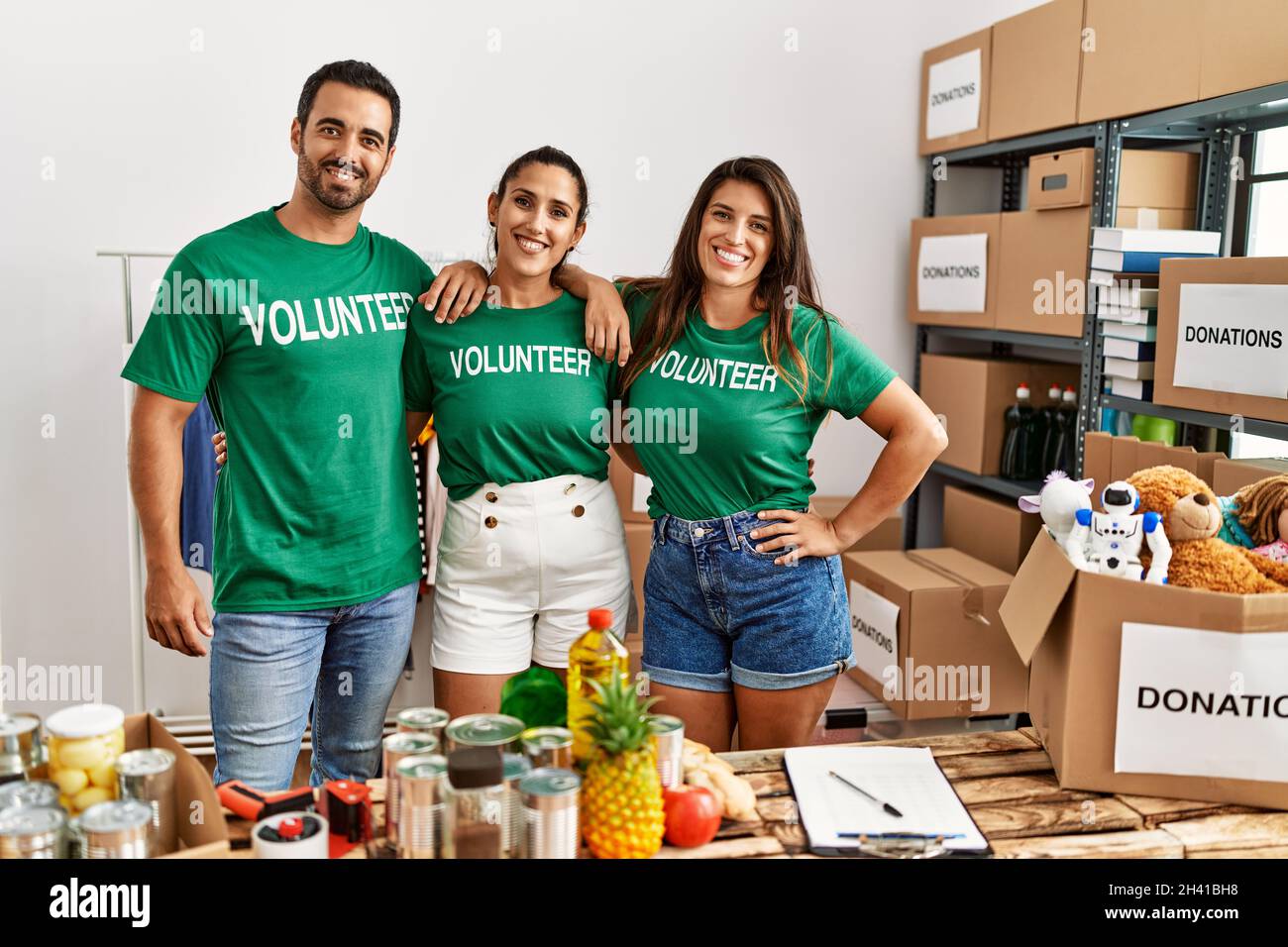 Group of hispanic volunteers smiling happy standing at charity center ...