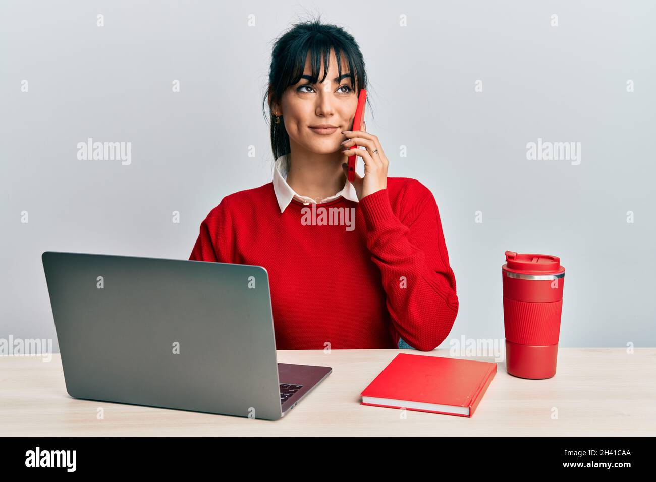 Young brunette woman with bangs working at the office talking on the ...