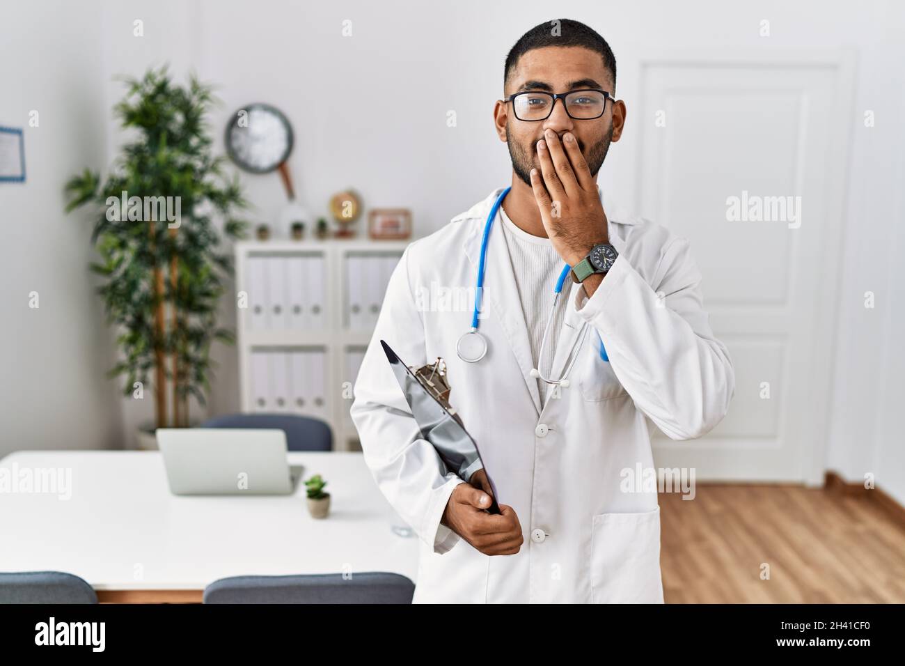 Young indian man wearing doctor uniform and stethoscope laughing and ...