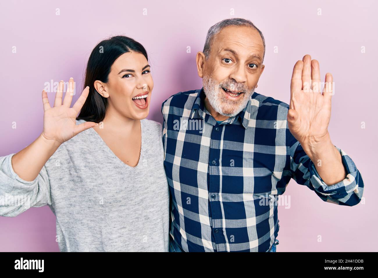 Hispanic father and daughter wearing casual clothes waiving saying ...