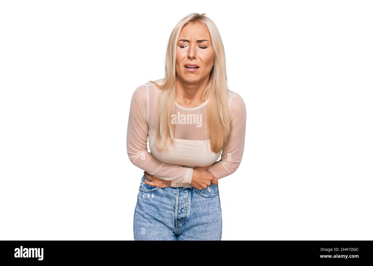 Young blonde woman wearing casual clothes with hand on stomach because ...